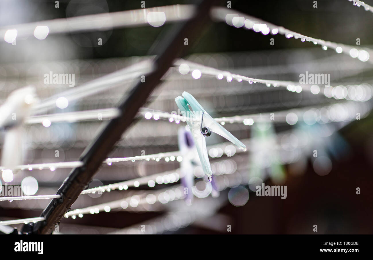 Clothes pegs on a washing line dripping rain water in very narrow focus ...
