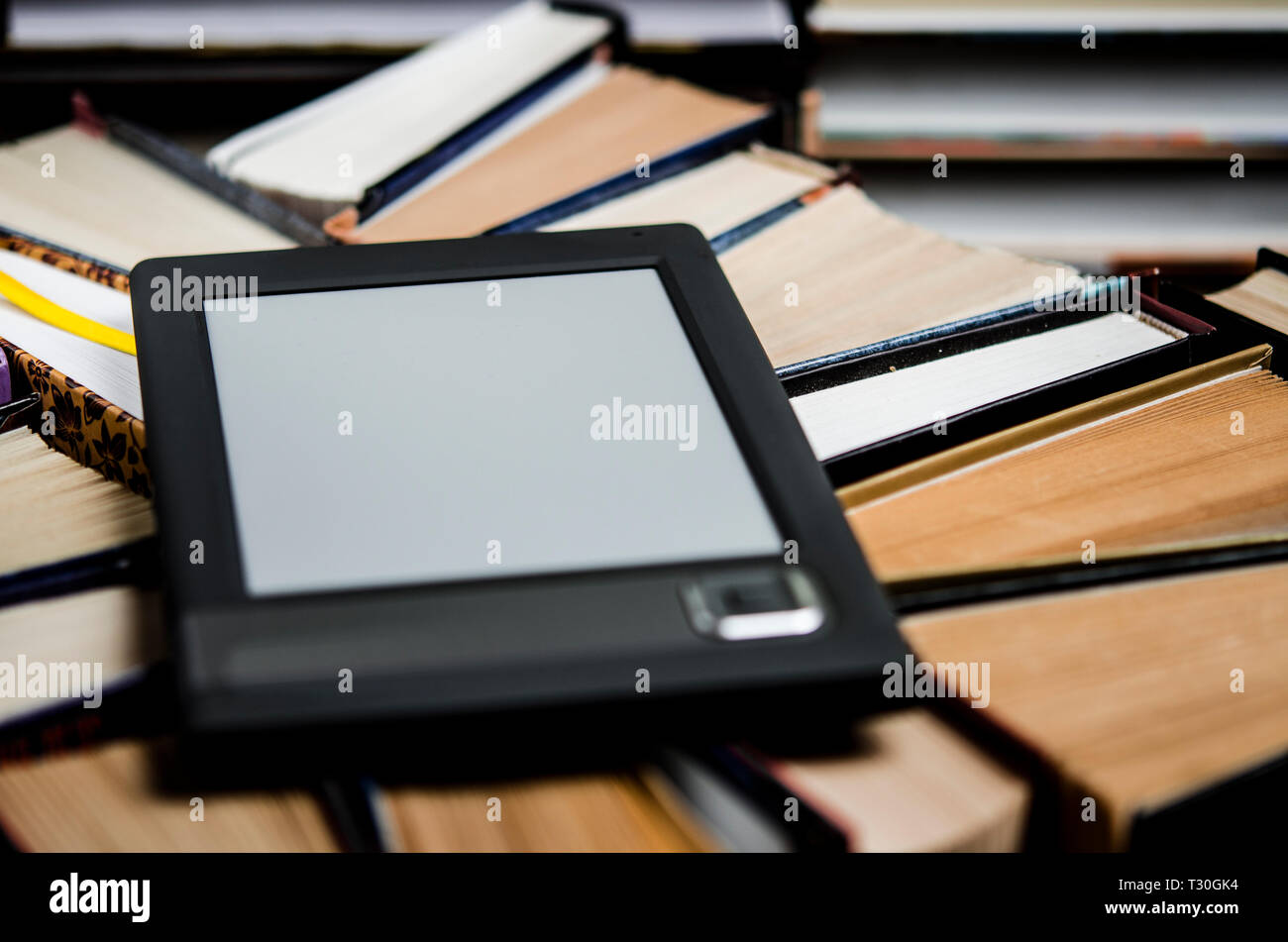 The e-book with a white screen lies on the open multi-colored books ...