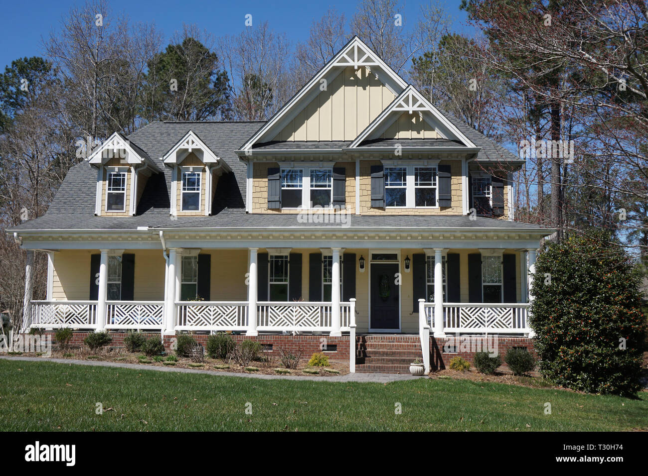 Suburban home with a yellow exterior and a large porch Stock Photo - Alamy