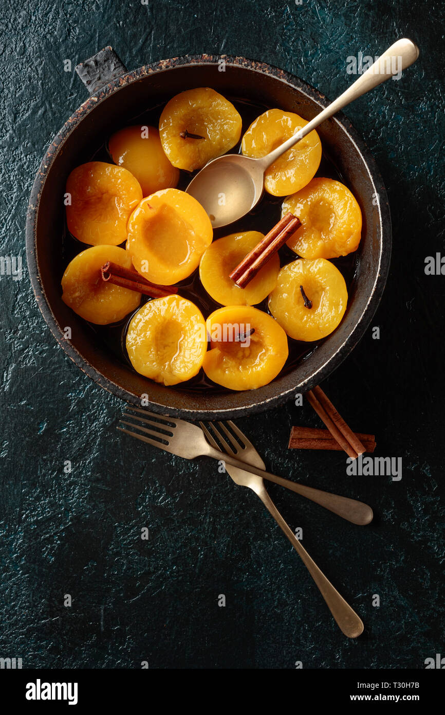 Peach dessert with cinnamon and cloves on a dark background, top view ...
