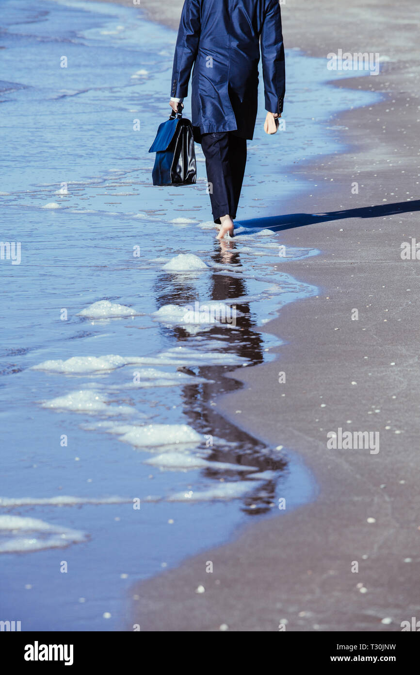 A lone man in a raincoat, with a briefcase strolling along the edge of ...