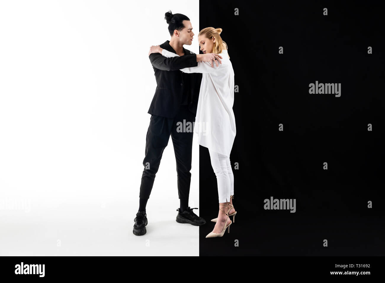 Hugging while posing. Young stylish diligent models wearing plain white ...