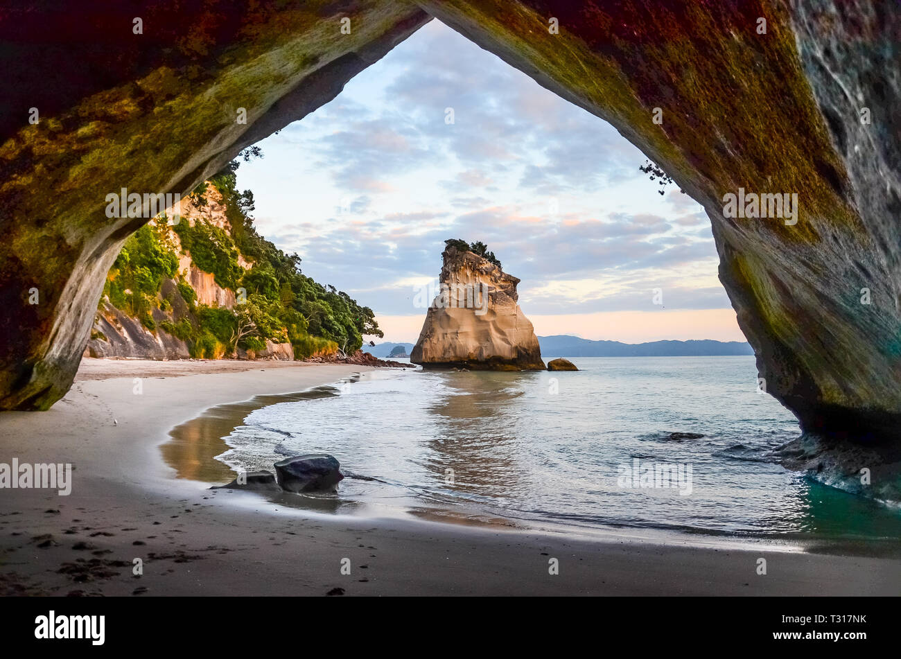 Sunrise at Cathedral Cove with blue sky with white clouds above and ...