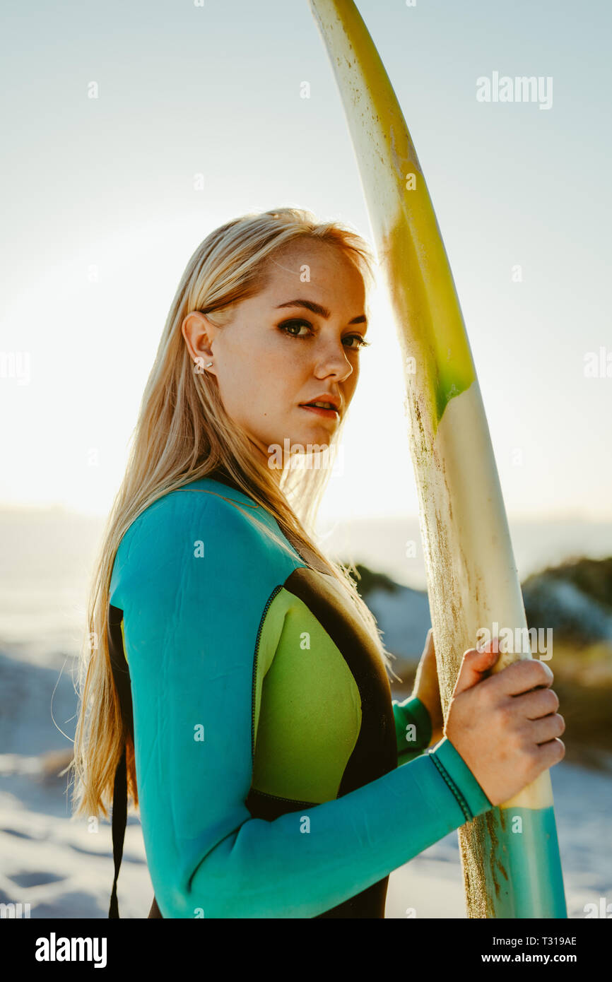 Woman surfer with surfboard standing on the beach. Female surfer with ...