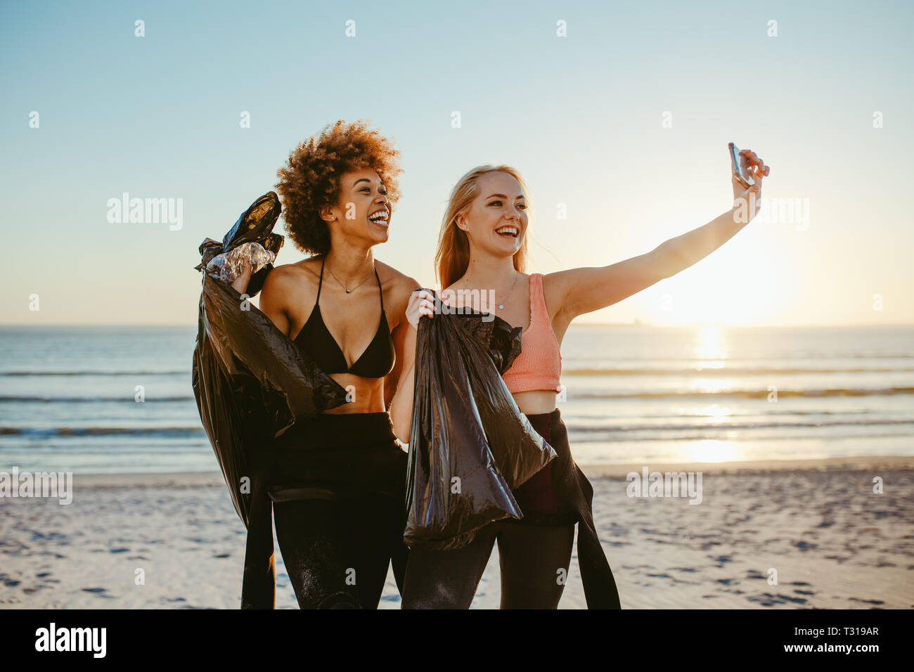 Two people collecting trash on a beach hi-res stock photography and ...