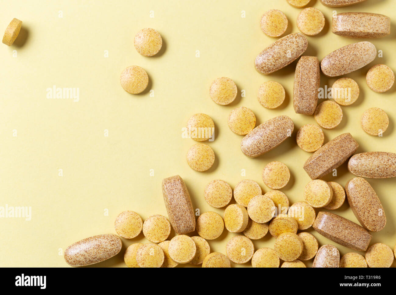 Top view of the heap of yellow medicine pills on yellow surface ...