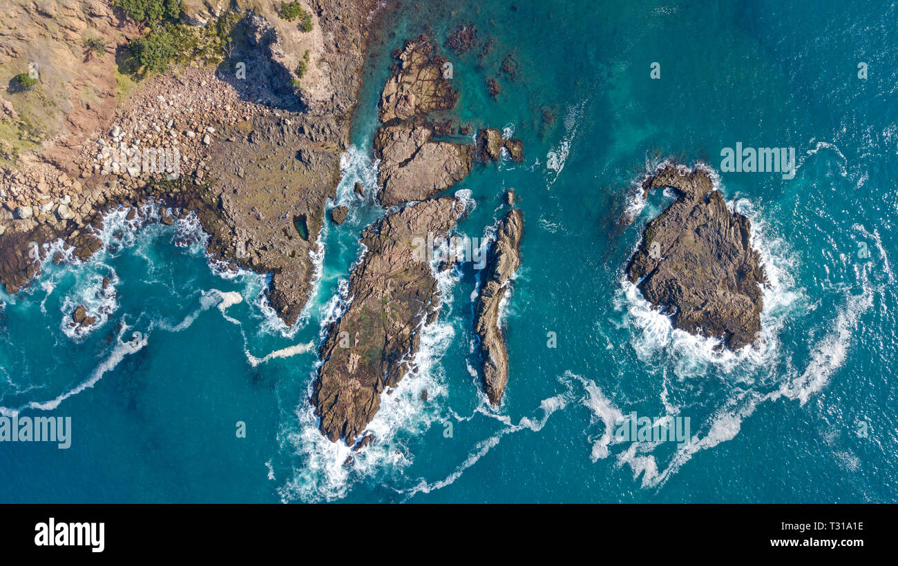 aerial view, top shot of the big waves hitting the rocks in the beach ...