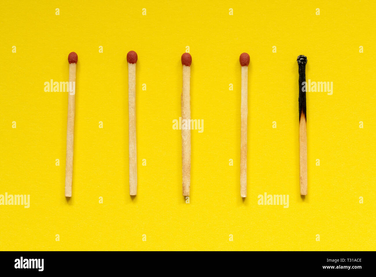 Wooden matches with one burned out on yellow background Stock Photo - Alamy