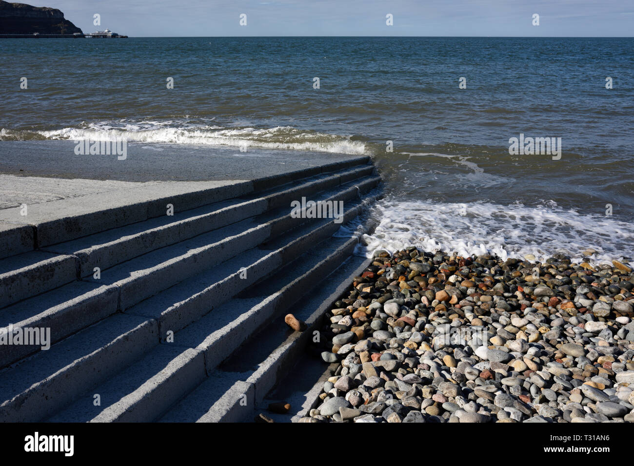 Concrete steps on side of slipway with sea lapping at base and onto ...