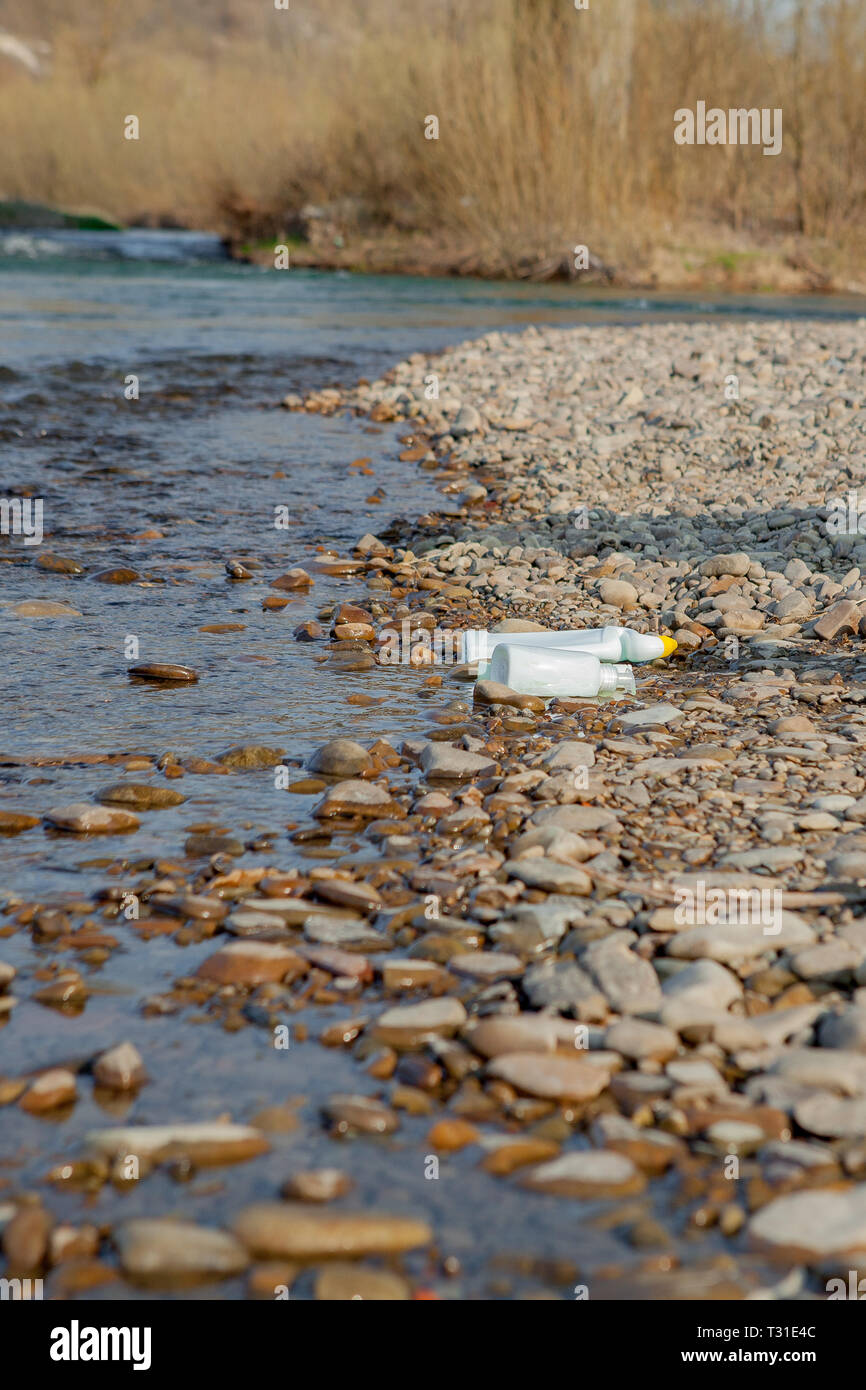 River pollution near the shore, garbage near the river, plastic food ...