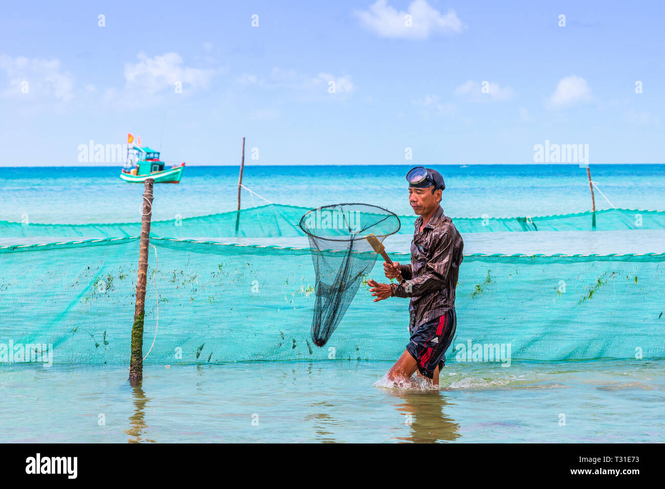 Local Vietnamese fisherman using a hand net and fishing nets off shore ...