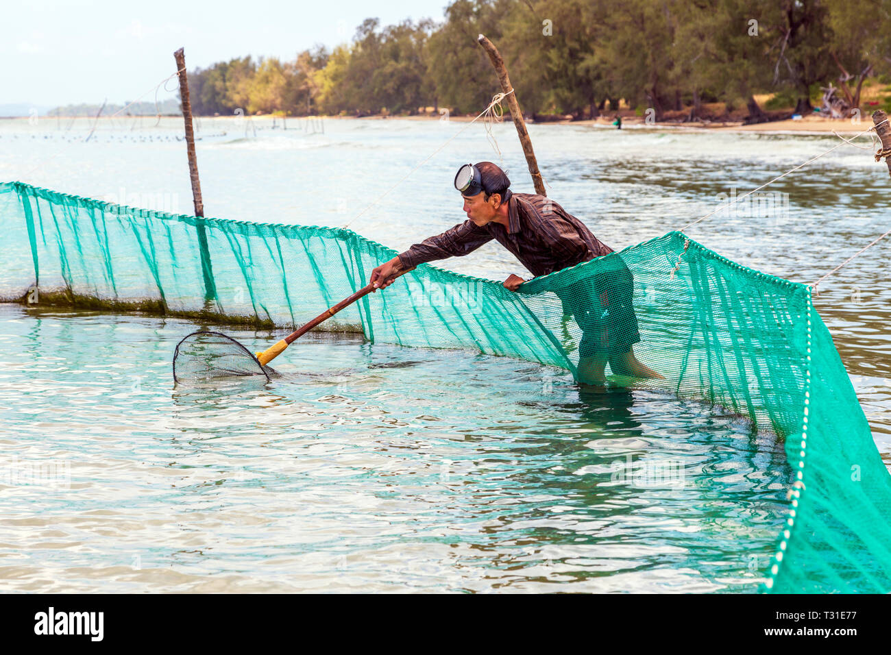 Local Vietnamese fisherman using a hand net and fishing nets off shore ...