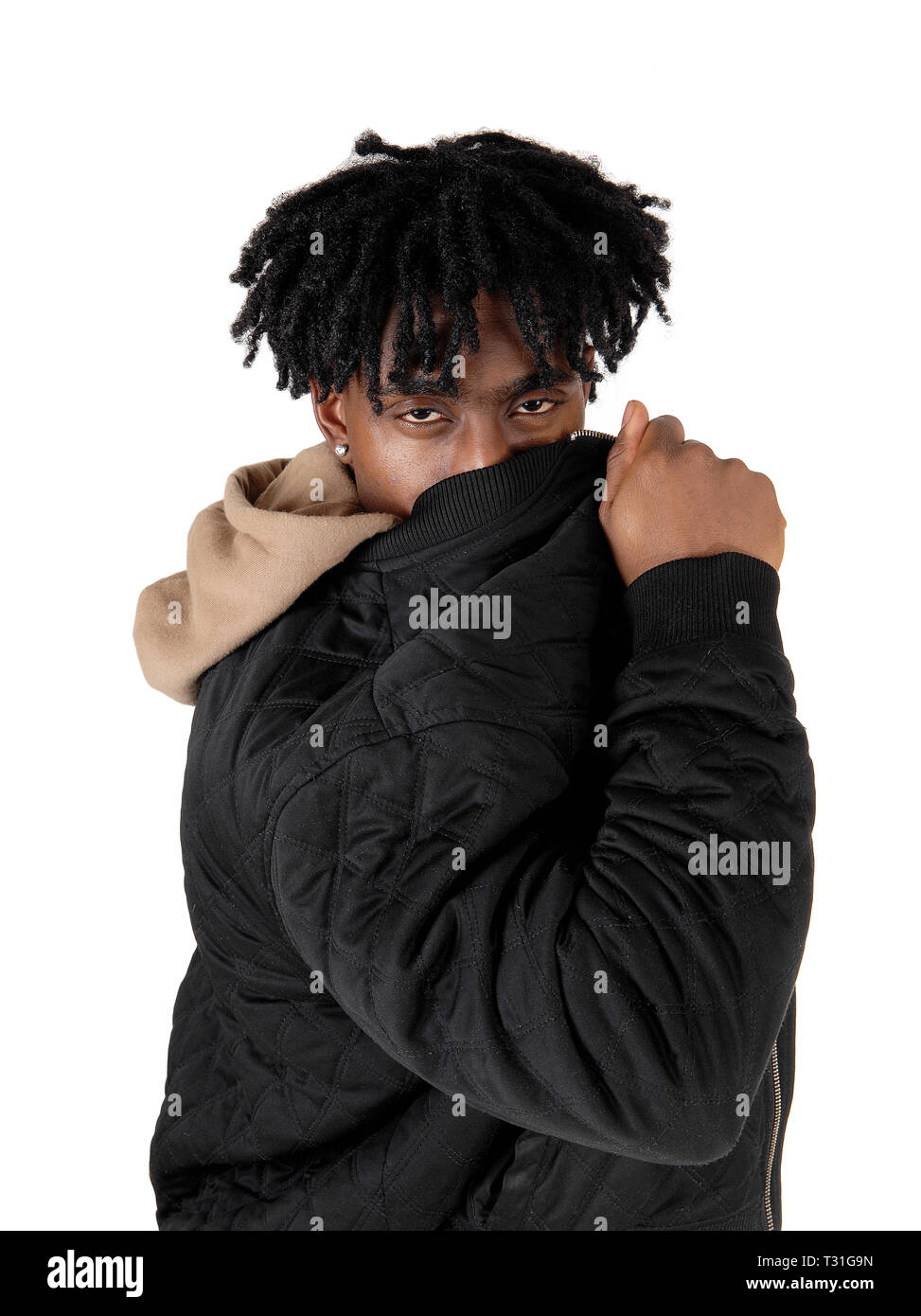 An African American man standing in the studio hiding his face behind ...