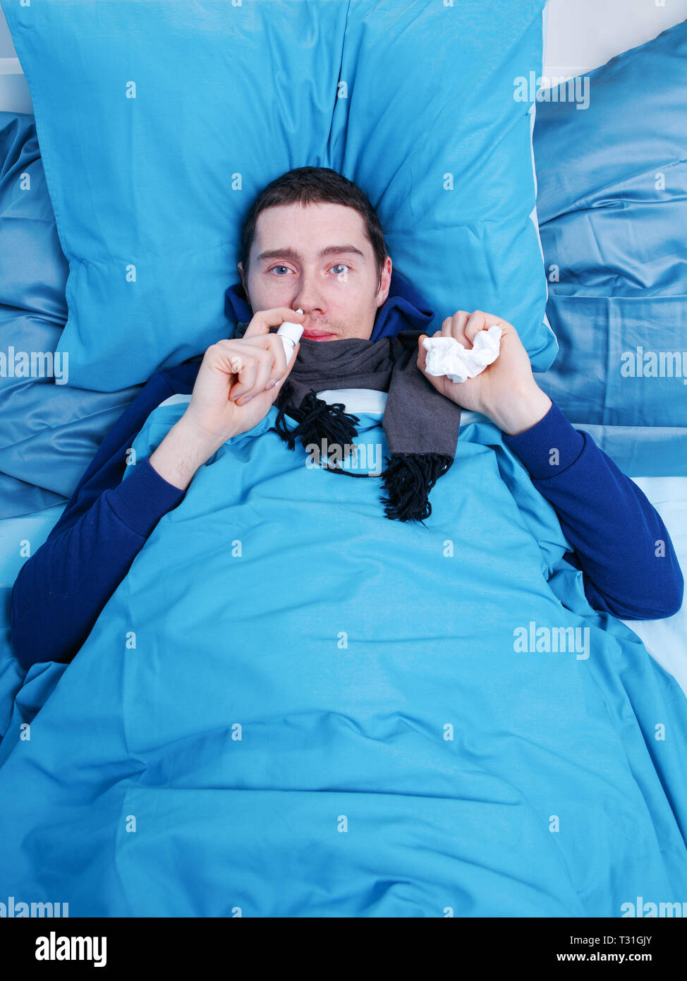 Sick brunet man using nasal spray while lying in bed Stock Photo - Alamy