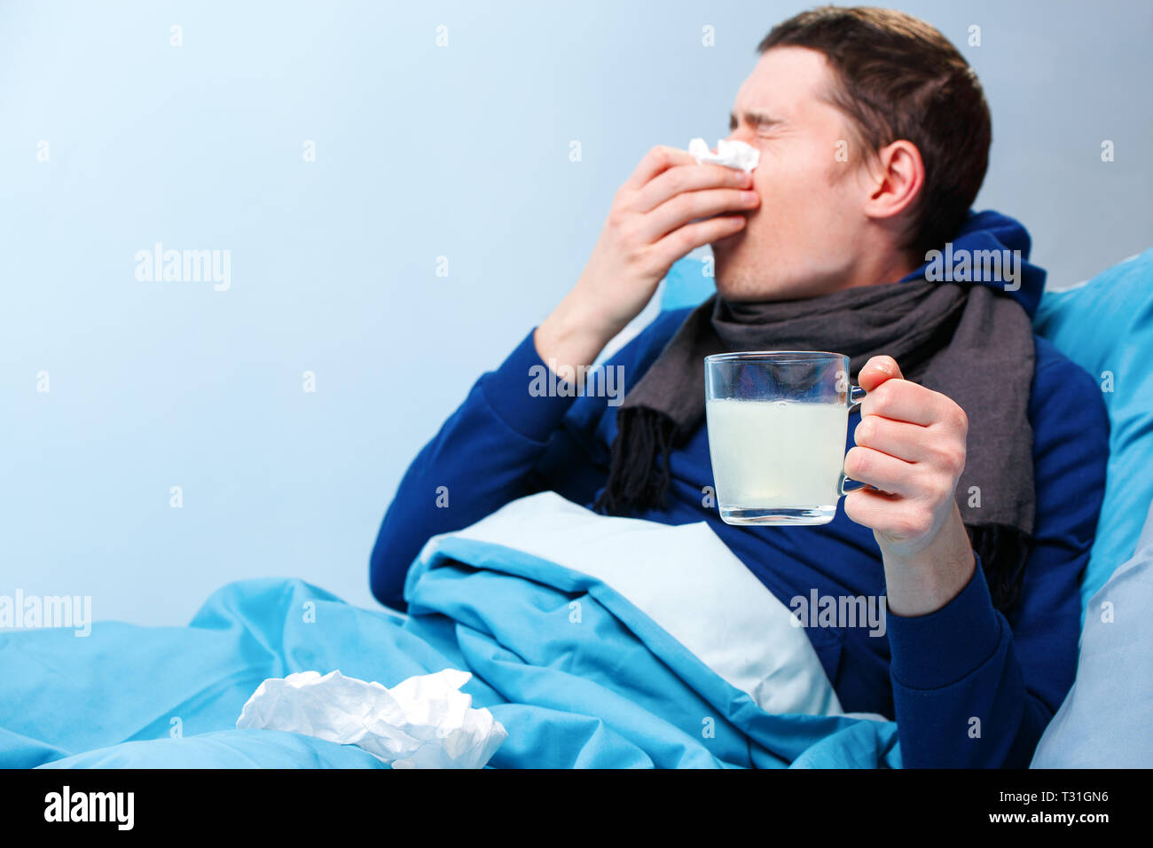 Photo of sick man in scarf with cup of medicine lying in bed Stock ...