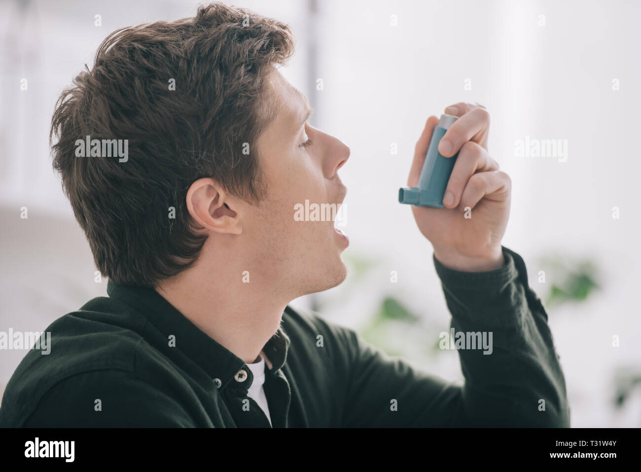 side view of handsome man using inhaler at home Stock Photo - Alamy