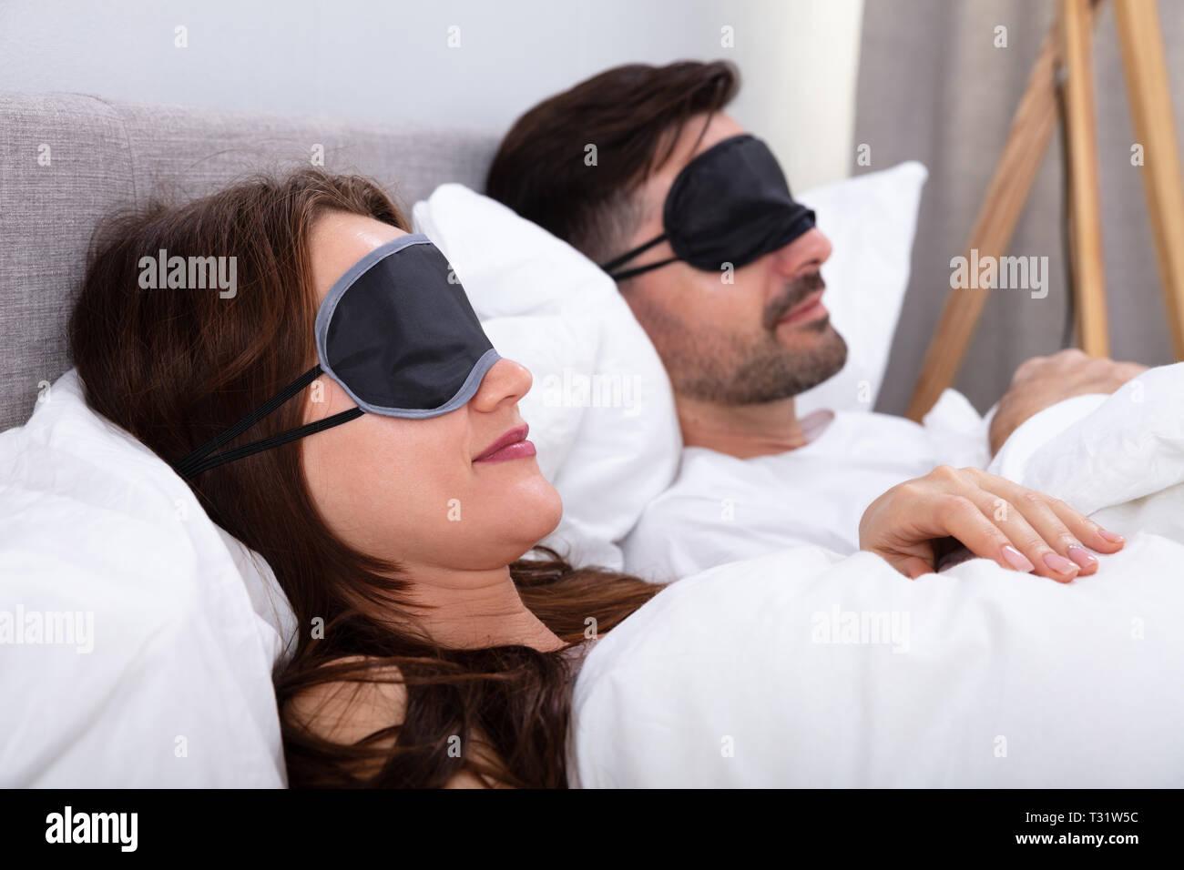 Young Couple Sleeping On Bed Using Eye Mask In Bedroom Stock Photo - Alamy