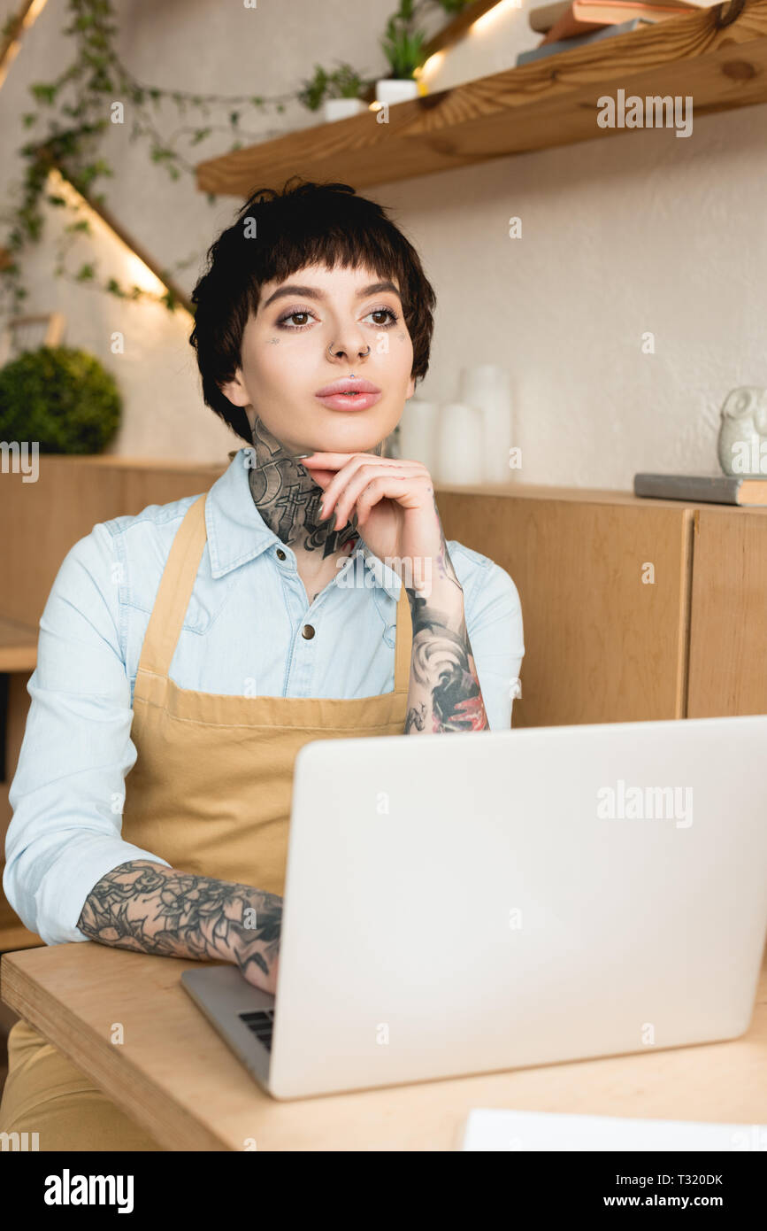 dreamy waitress using laptop in coffee shop and looking away Stock ...