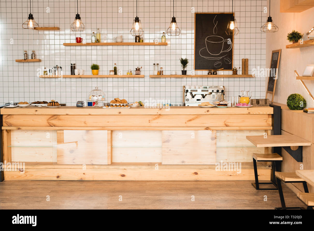 interior of cafeteria with wooden bar counter, shelves and board with ...