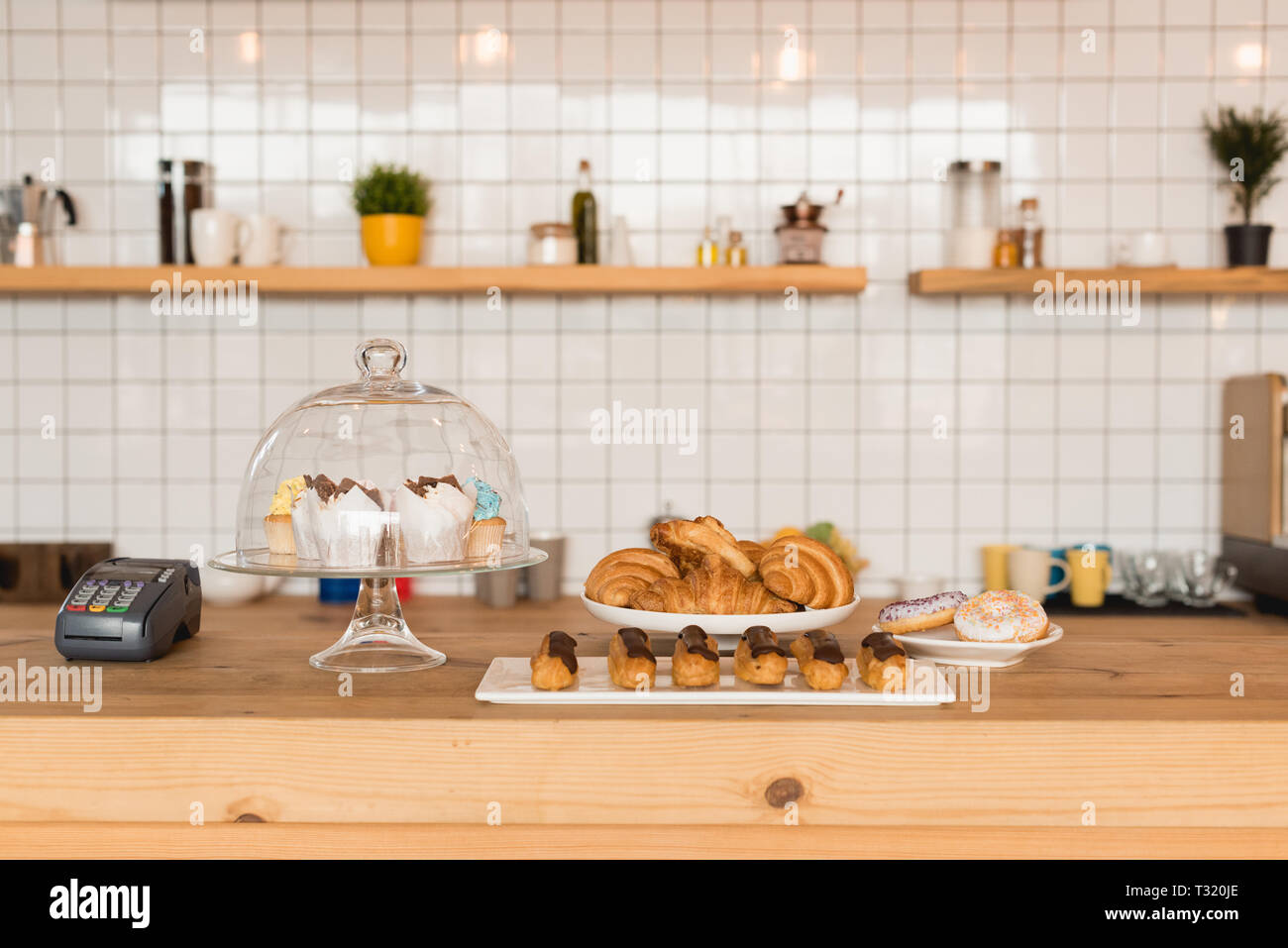 bar counter with cake stand and dishes with delicious desserts and ...