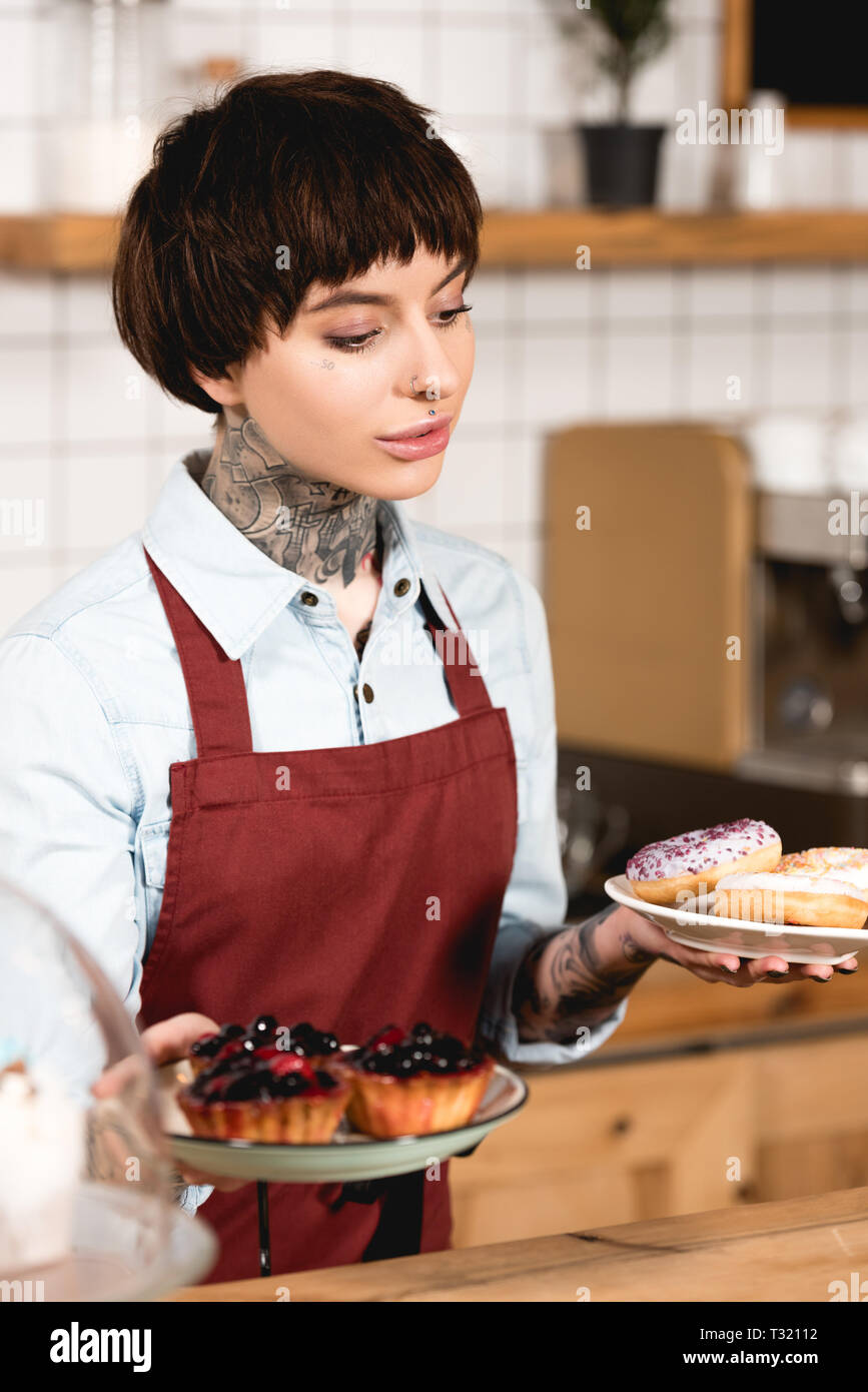 beautiful barista holding plates with delicious pastry in coffee shop ...
