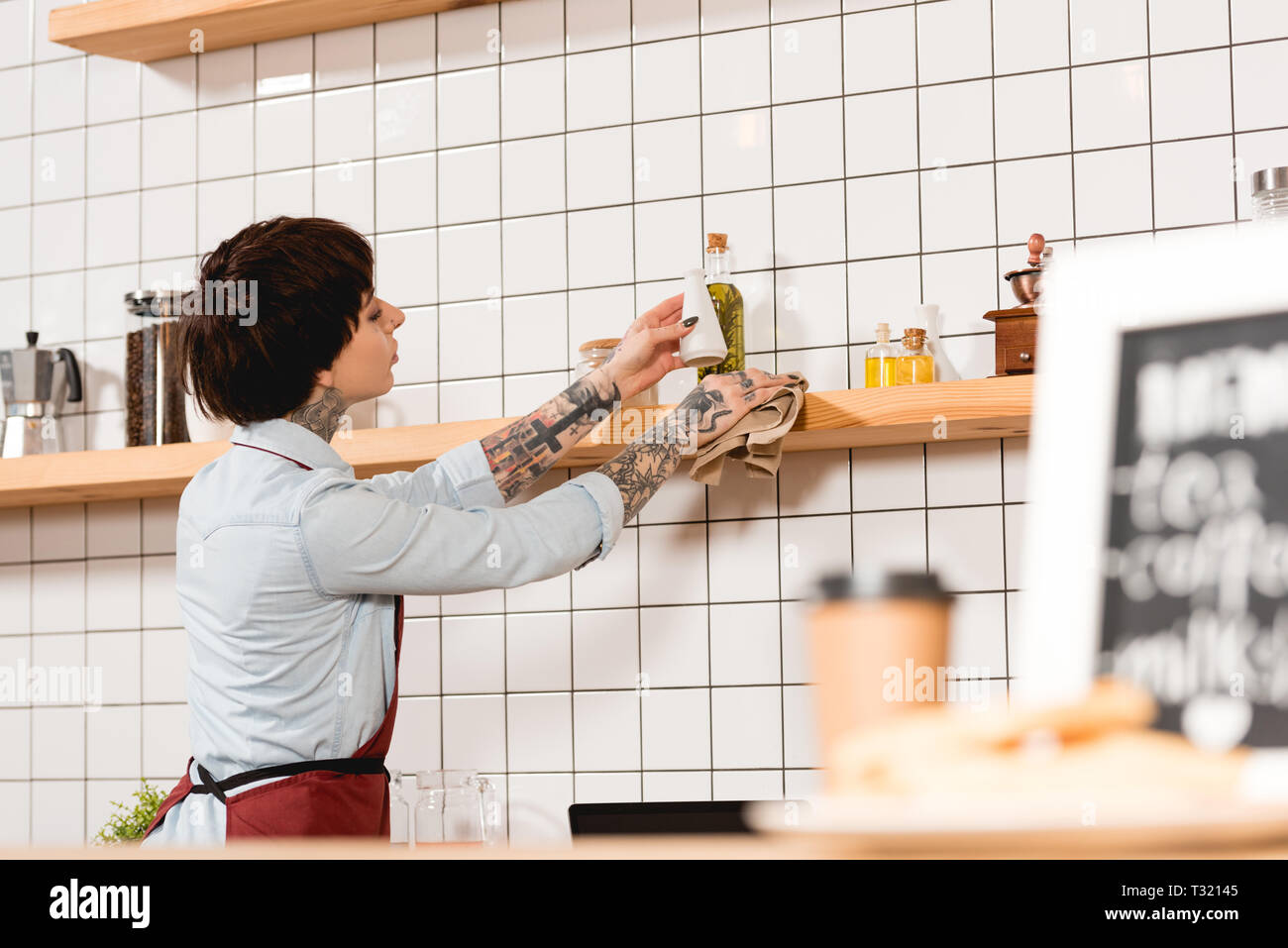 selective focus of barista cleaning wooden shelf in coffee shop Stock ...
