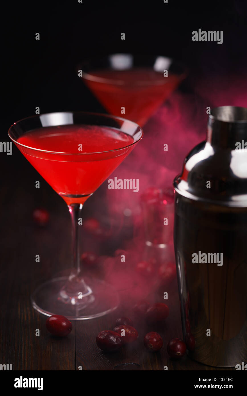 Cosmopolitan cocktail with cranberries, shaker and jigger on a dark ...