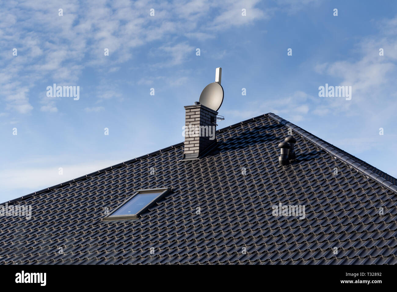 Roof of a house with chimney, satellite dish and window under blue sky ...