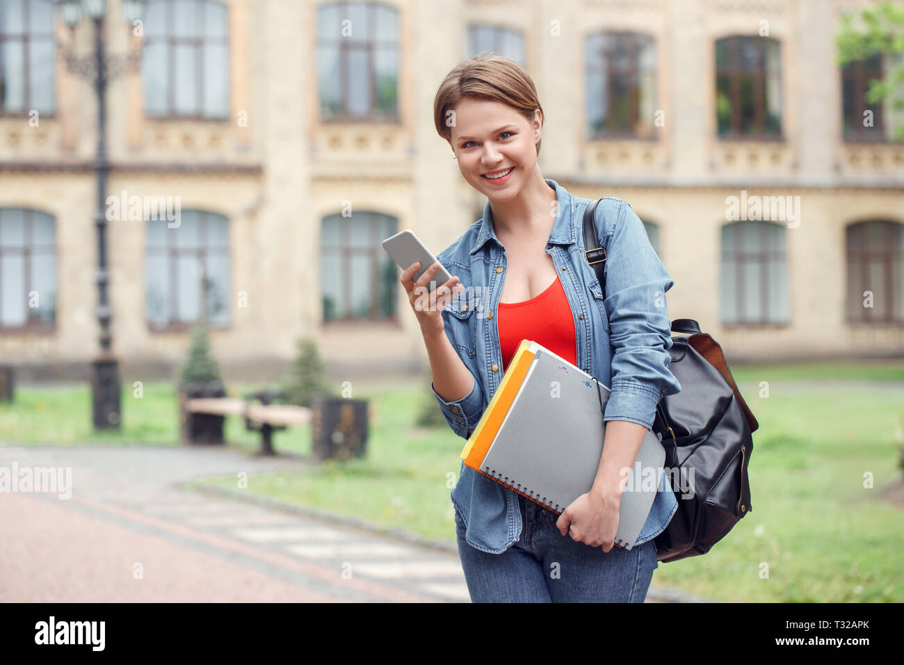 Young female student carrying backpack at university campus standing ...