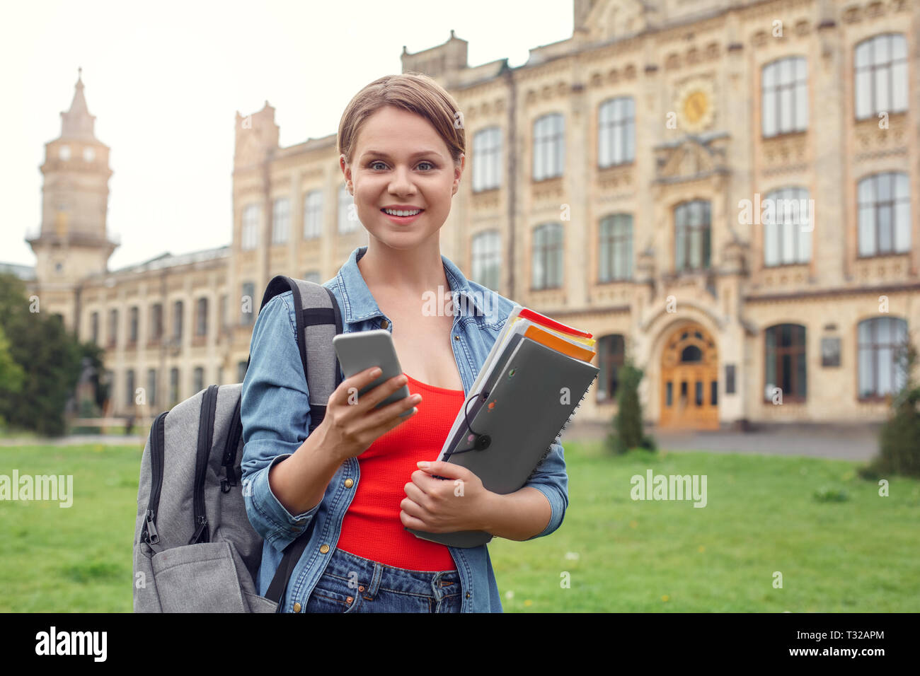 Young female student carrying backpack at university campus walking ...