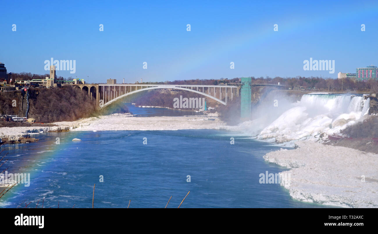 NIAGARA FALLS, NY -27 MAR 2019- View of a rainbow over frozen ice and ...