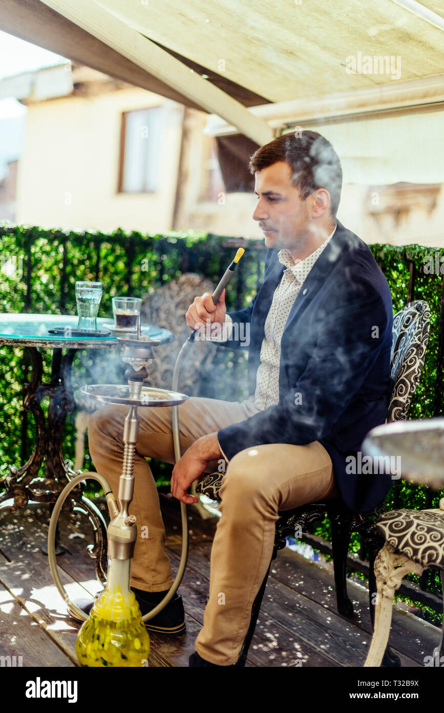 Attractive man on terrace enjoying in the sun while smoke shisha Stock ...