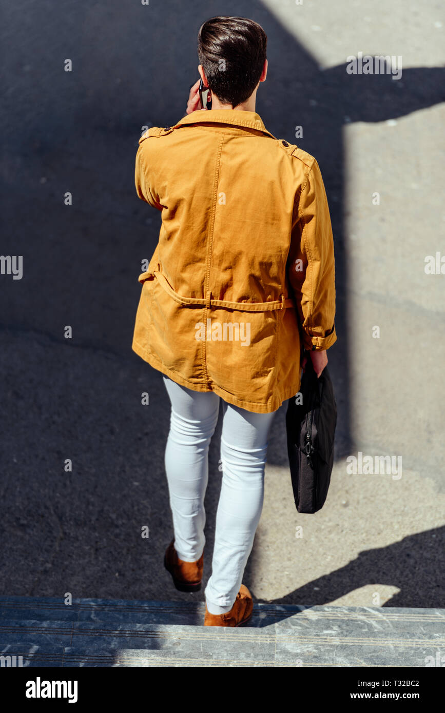Young businessman walking outdoors while talking on cellphone Stock ...