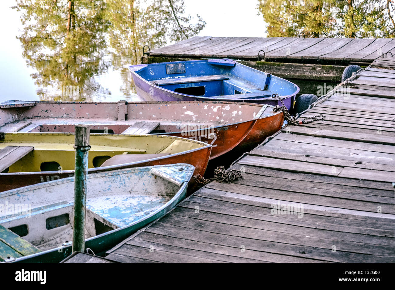 Old iron frayed and shabby boat tied to wooden dock close-up Stock ...
