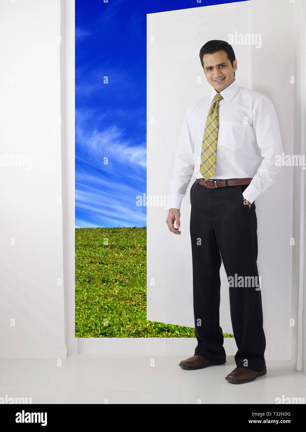 A PORTRAIT OF A YOUNG MAN IN HIS HOME STANDING NEAR HIS DOOR WITH A ...