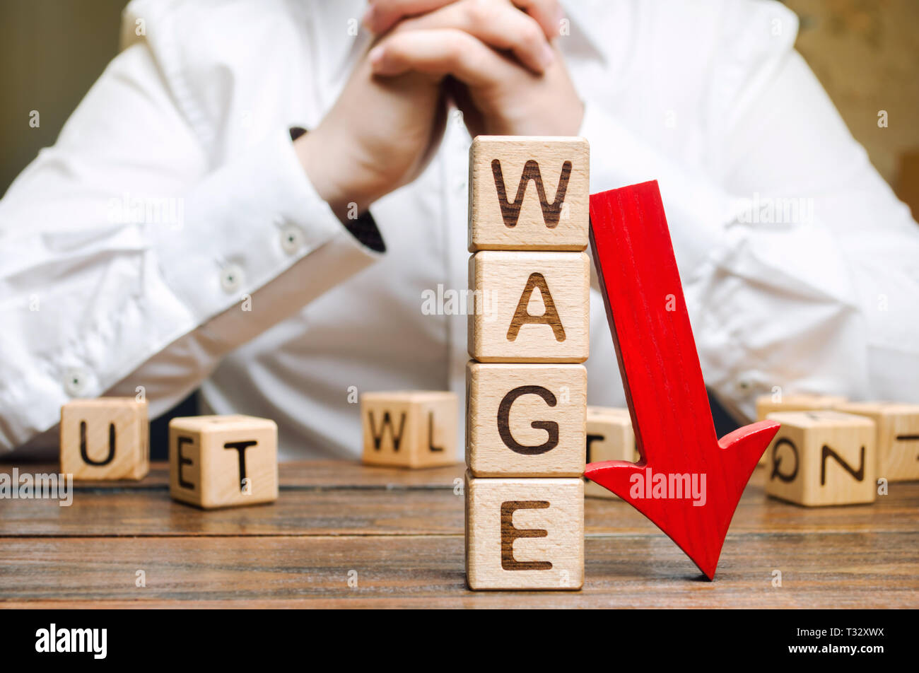 Wooden blocks with the word Wage and red arrow down. Salary reduction ...
