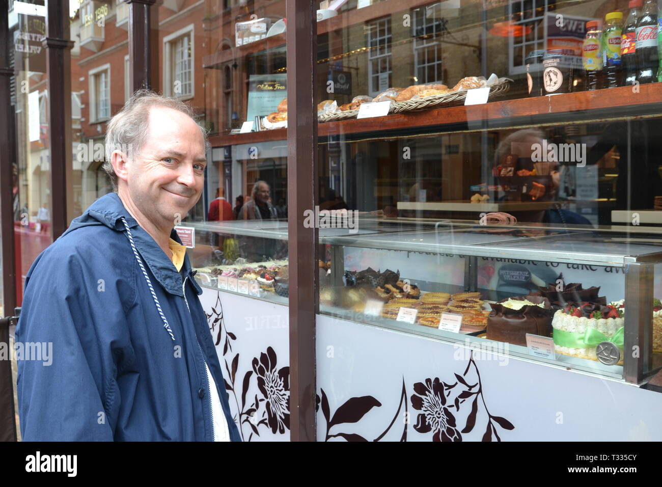 Man looking into cake shop window with a smile, in Ipswich, Suffolk, UK ...