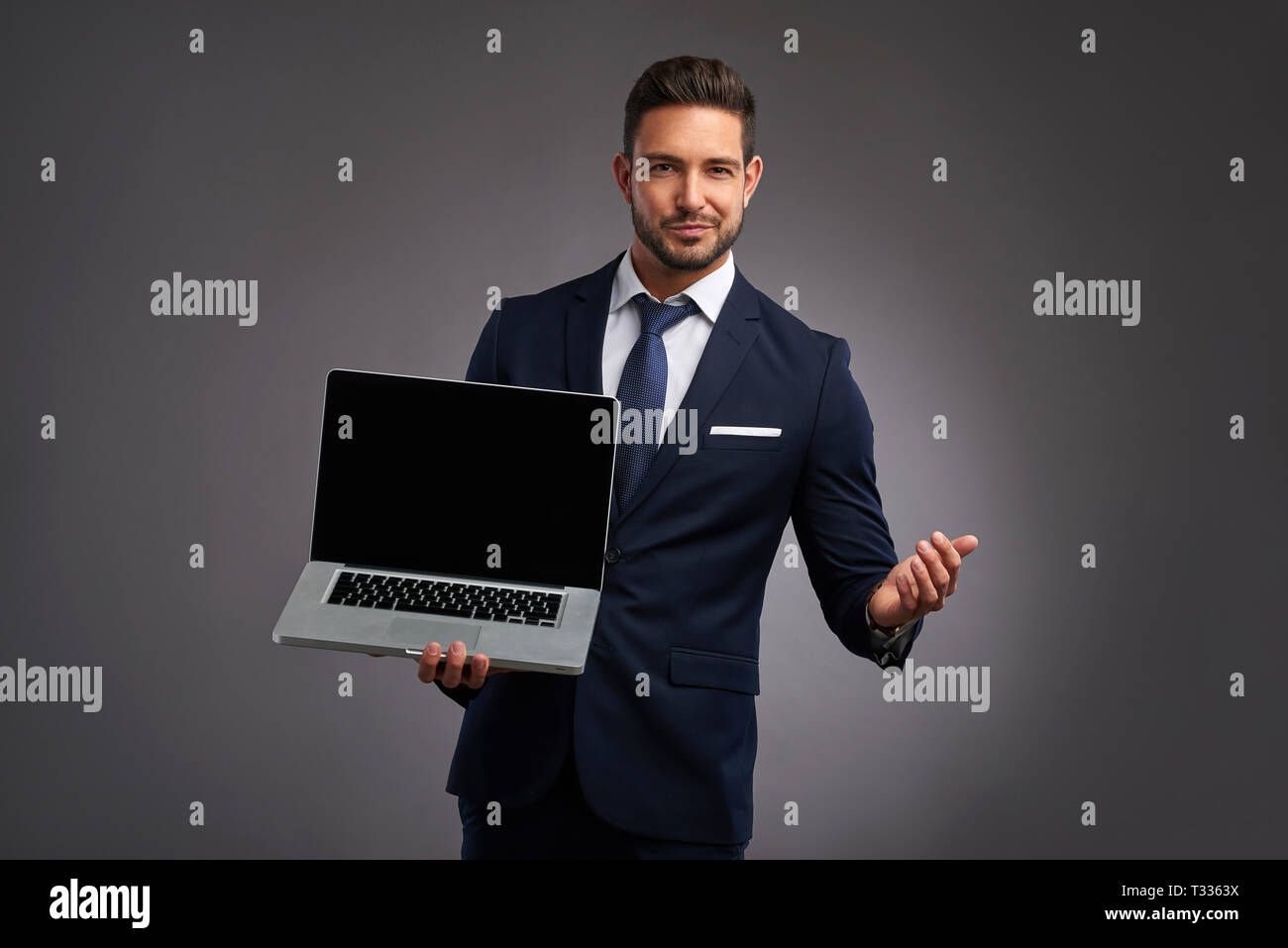 An elegant handsome young man holding and showing the screen of a ...