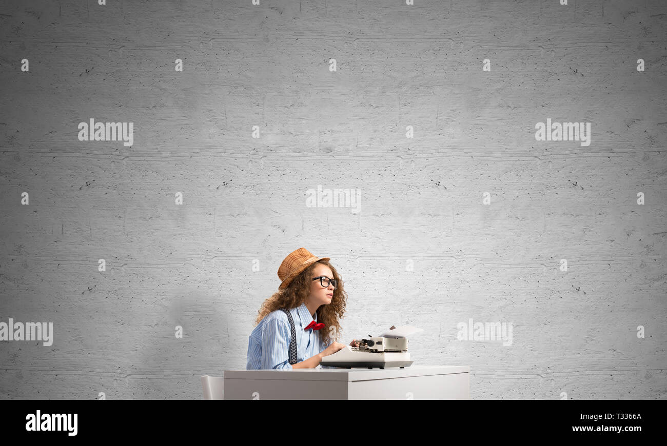 Side view of young beautiful woman writer in hat and eyeglasses using ...
