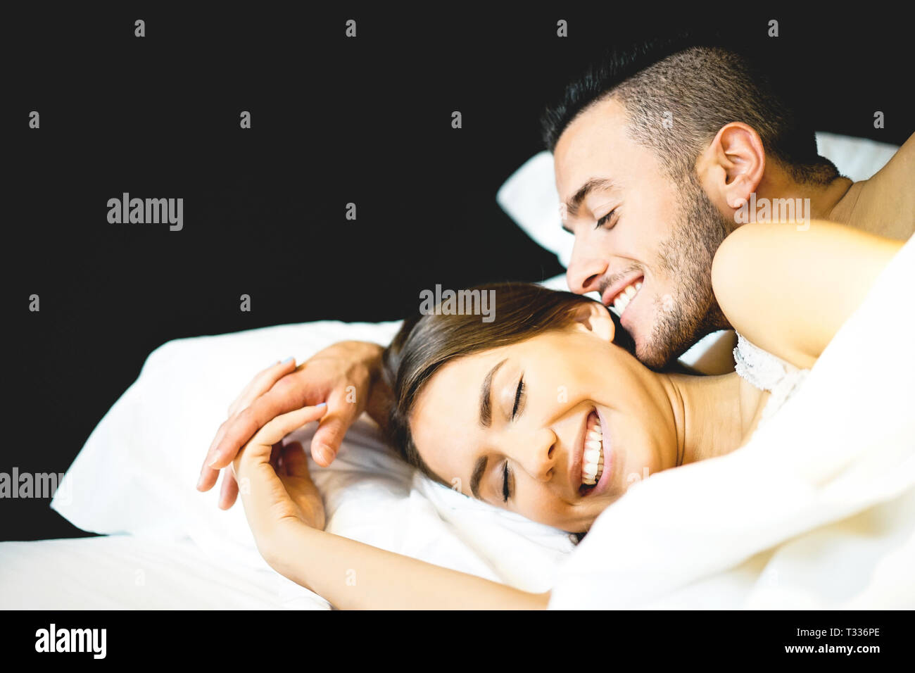 Young sexy couple of lovers lying on bed in their honeymoon - Young bearded man whispers and ...