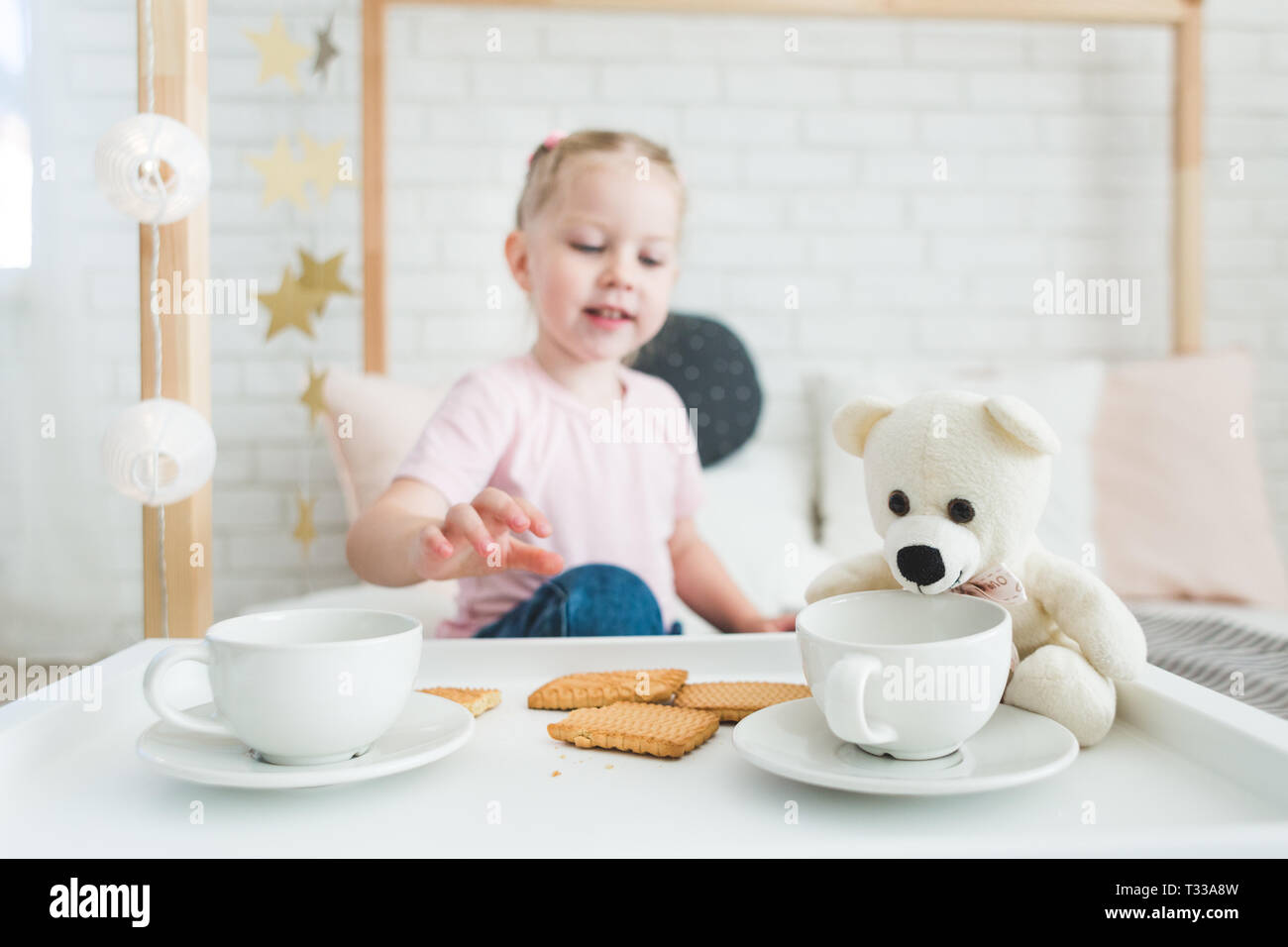 Cute little girl drinks tea with her teddy bear Stock Photo - Alamy