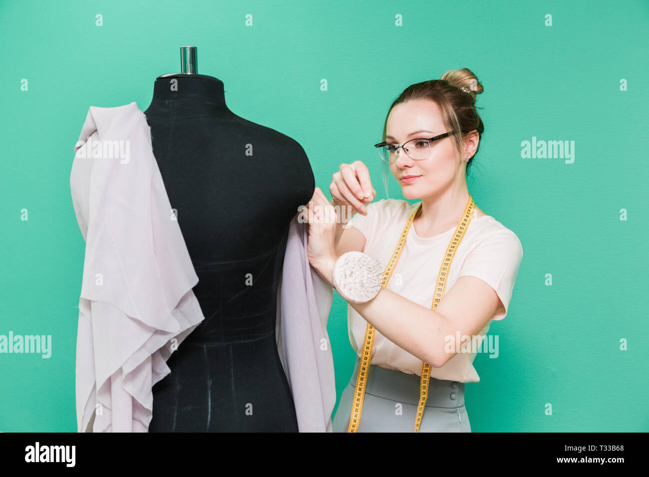 Sewing workshop. Seamstress at work. Young dressmaker working on dress ...