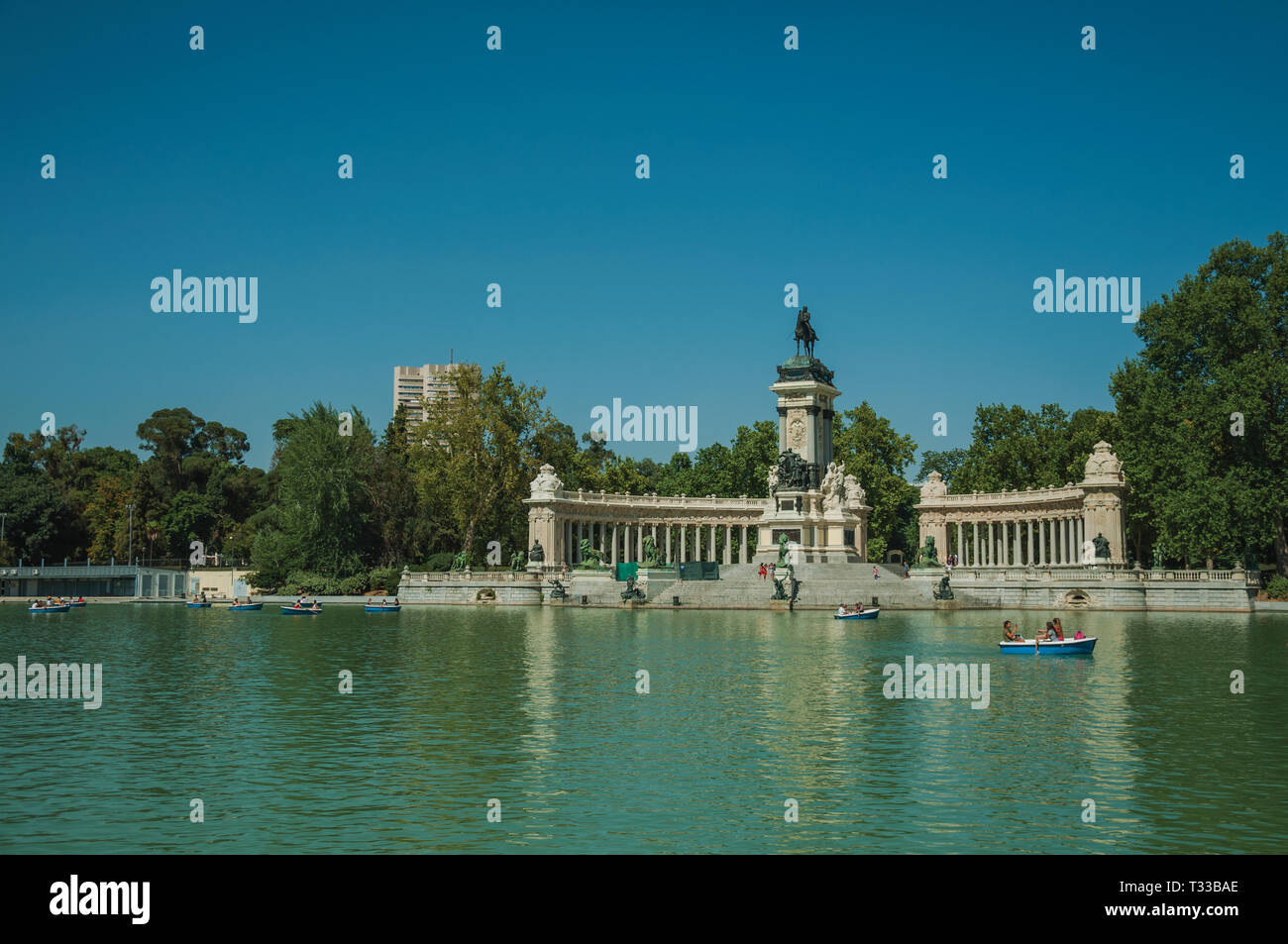 People paddling boats on the reflecting pool and monument at El Retiro ...