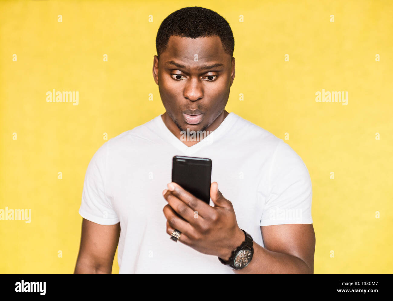 Perplexed and worried handsome African American man holds smartphone ...
