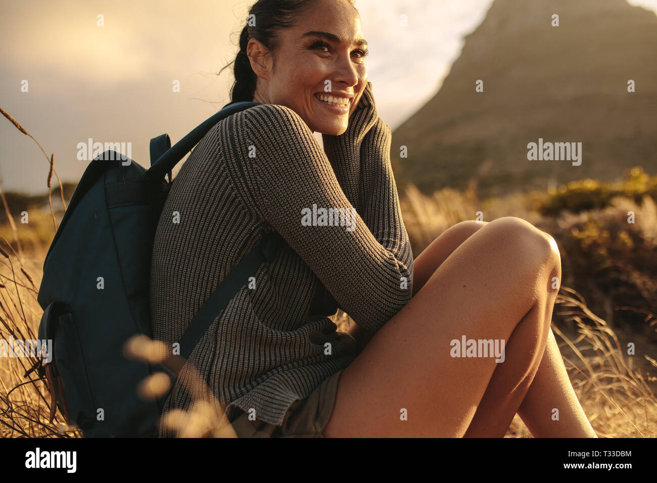 Young woman taking rest while hiking in nature. Female hiker sitting on ...