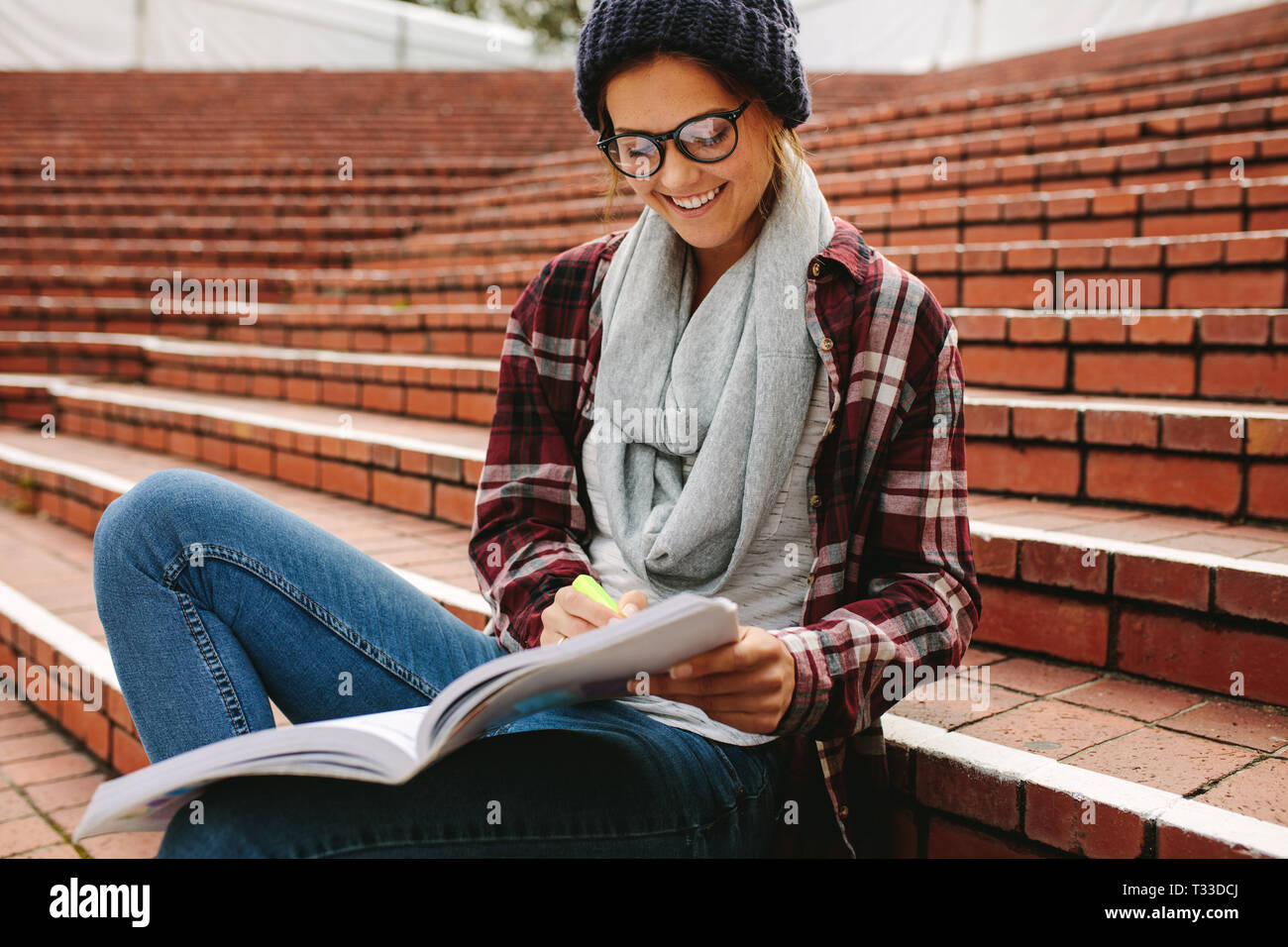 Female college student sitting on campus with pen and book. Woman in ...