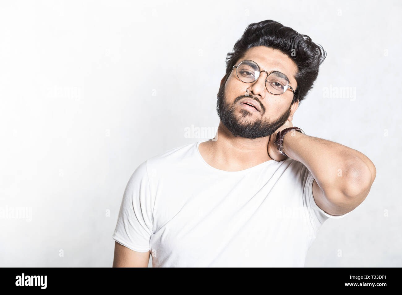 Attractive young man keeps hand on neck, tries to relieve muscle ...