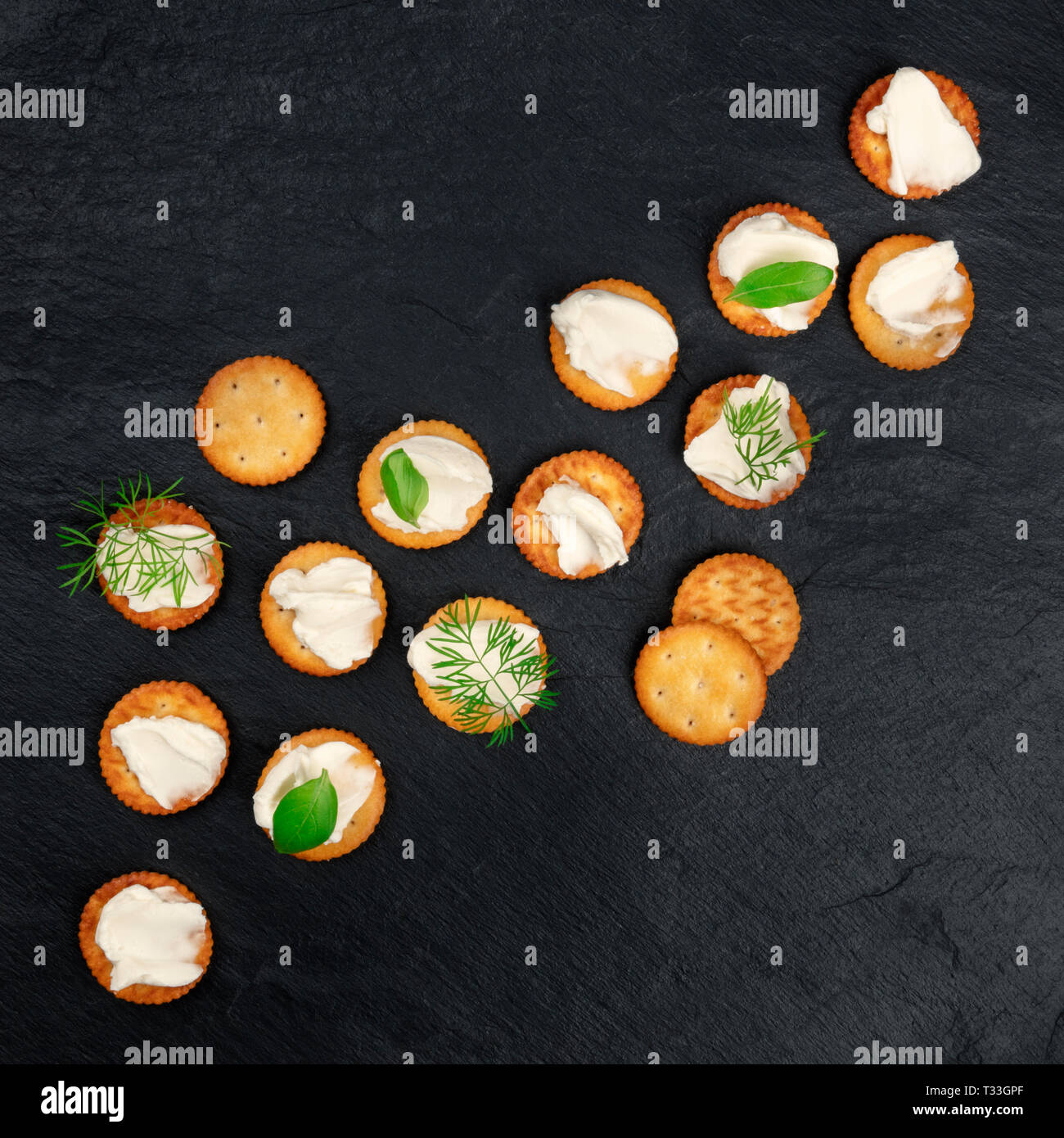 Salt crackers with soft cream cheese spread and herbs, shot from the ...