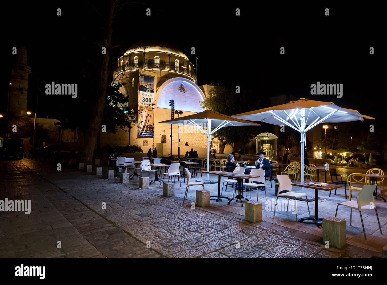 Terrace cafe with a pair of visitors in the square near the synagogue ...
