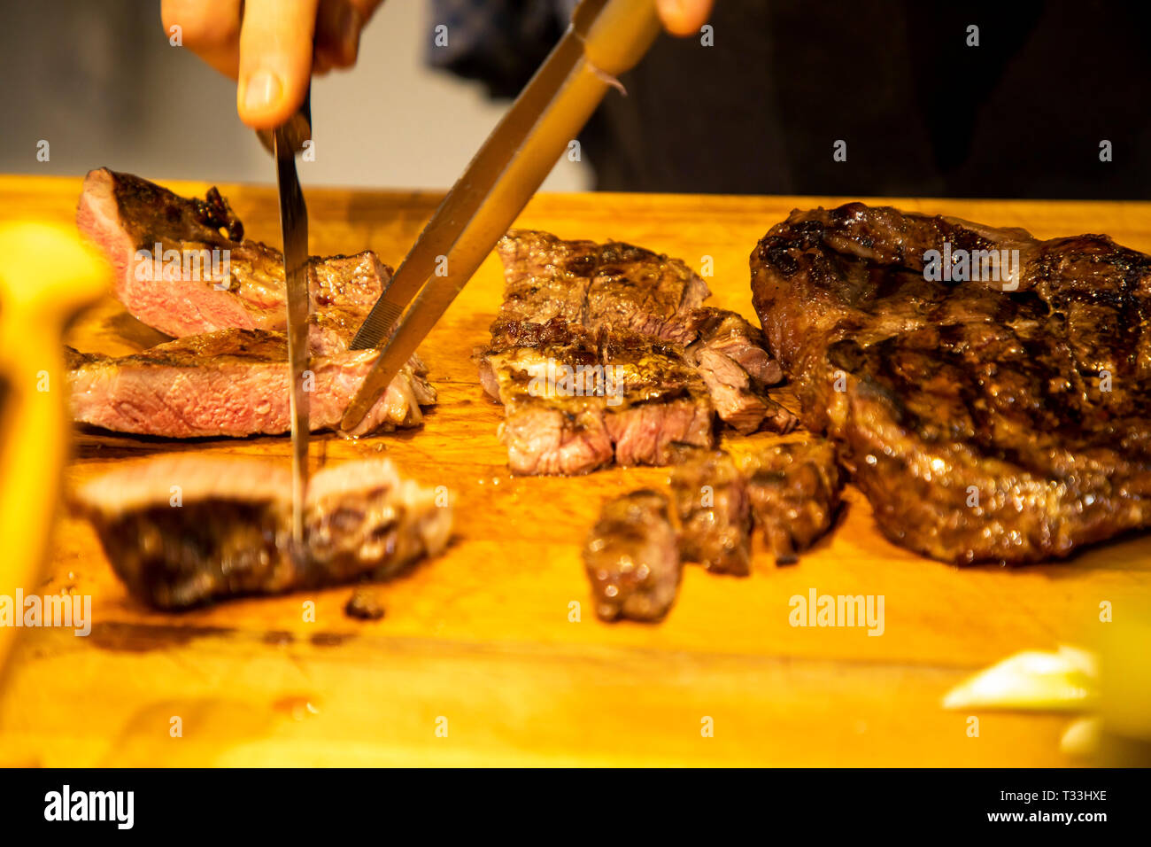 Grilled meat, beef, is cut portion by portion by the cook Stock Photo ...
